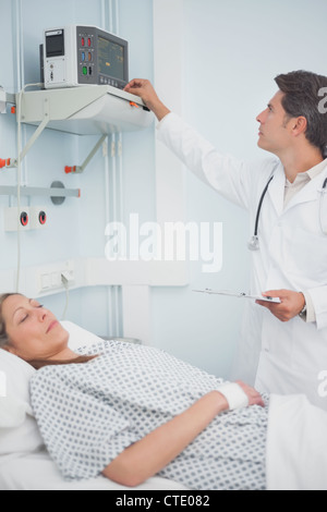 Female doctor adjusting medical monitor while female patient sitting on ...