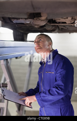 Mechanic looking at the below of a car Stock Photo - Alamy