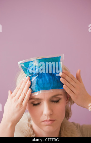 Woman applying ice pack to her head Stock Photo - Alamy