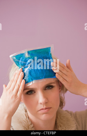 Woman applying ice pack to her head Stock Photo - Alamy