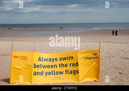 Red & Yellow RNLI Safety Flags on the beach with cloudy blue skies ...