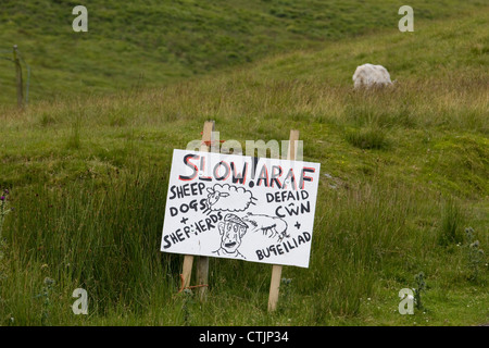 SLOW DOWN (ARAF) ROAD SIGN IN WELSH AND ENGLISH WITH CAR IN BACKGROUND ...