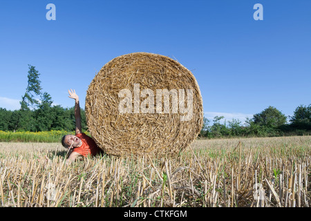 funny man being crushed by a rolling Hay bale Stock Photo - Alamy