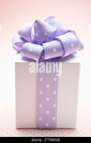 purple gift box tied with ribbon on a gray background, top view ...