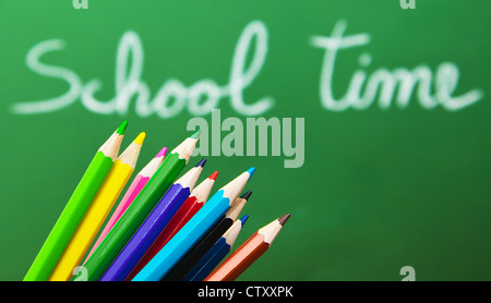 Chalkboard with text SCHOOL TIME and stationery on color background ...