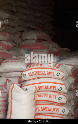 Stack of brown burlap sacks with grain at a warehouse. Big pile of hemp ...