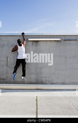 Man scaling wall on city street Stock Photo - Alamy