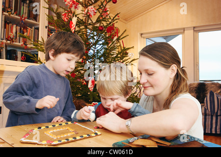 Family decorating gingerbread house on Christmas eve Stock Photo - Alamy