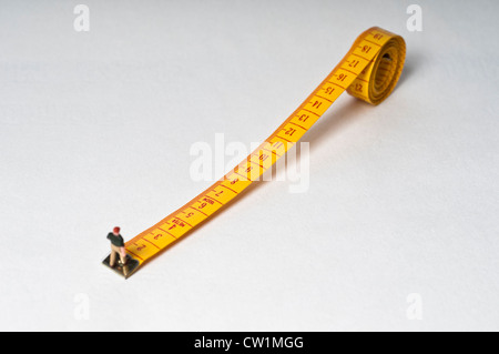 Toy figure climbing a tape measure Stock Photo - Alamy