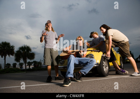 Friends enjoying music by a car at the parking area Stock Photo - Alamy