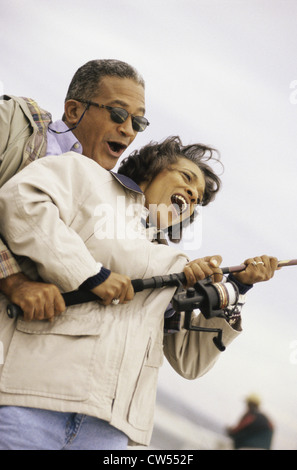 Smiling mid adult man fishing while standing on the deck of a boat with ...