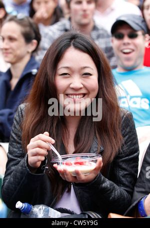 A spectator eating strawberries and cream on day nine of the 2025 ...