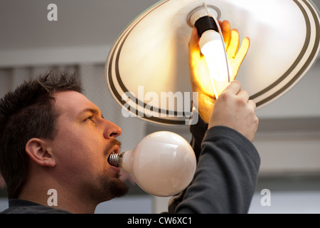 The man changes the lamp. Energy-saving lamp. Replacement of an energy ...