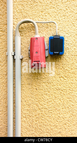 Two blue electric sockets in an vibrant orange wall, exterior electric ...