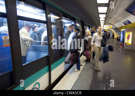People enter and exit the Paris Metro subway on a winter day at dusk ...