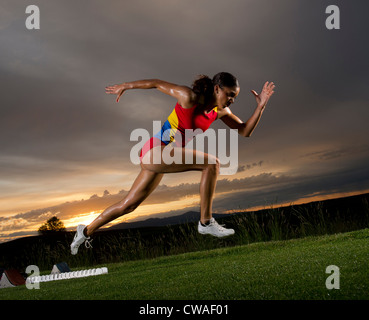 woman sprinter leaving starting blocks on the athletic track. Side view ...