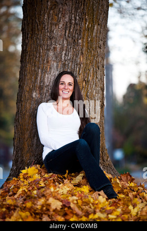 Young beautiful woman sitting under the tree on the ground coverd with ...