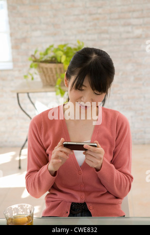 Young Asian woman using smartphone sitting on sofa relaxed casual at ...
