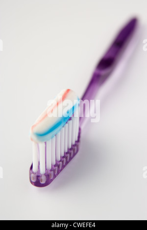 White and blue striped toothpaste on an orange toothbrush, white ...