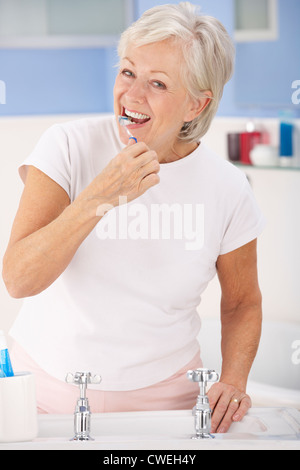Smiling woman brushing teeth in bathroom and looking at camera. Morning ...
