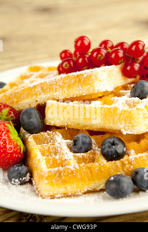 fresh tasty waffer with powder sugar and mixed fruits on wooden ...
