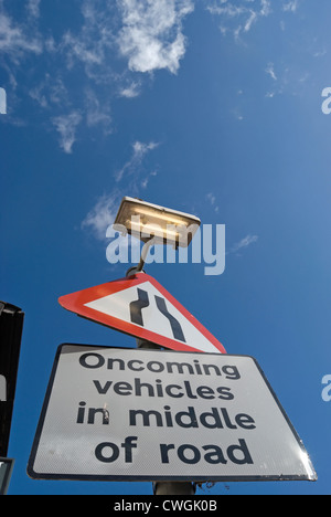 Road signs for road narrowing and oncoming vehicles in middle of road ...