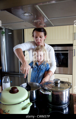 Polish mom helping daughter age 4 cook at stove. Zawady Central Poland ...