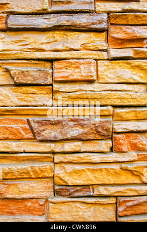 Close up of the façade of a brick wall with weathered yellow paint and ...