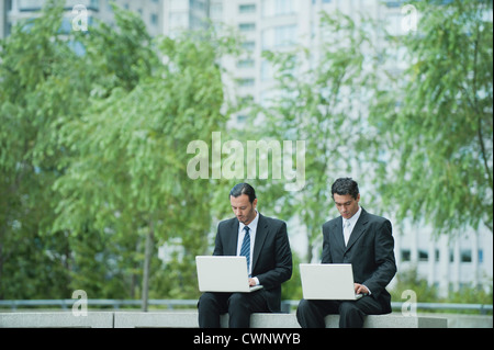 business people sitting side by side outside working and looking in the ...
