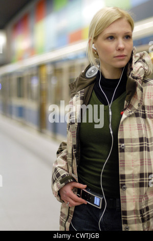 Young woman with earbuds in subway station Stock Photo - Alamy