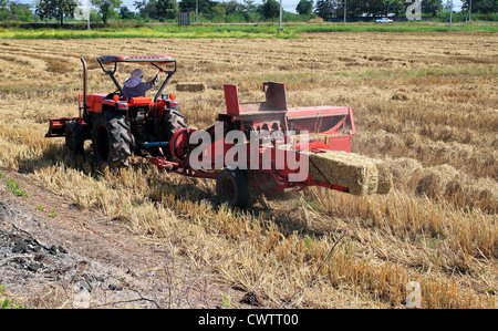 farmer and tractor packing straw in the field at Thailand Stock Photo ...