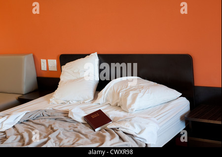 Motel room with bible and messy bed Stock Photo - Alamy