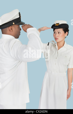 Multi-ethnic US Navy officers saluting each other over light blue ...