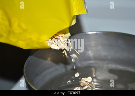 pouring oats into saucepan of water Stock Photo - Alamy