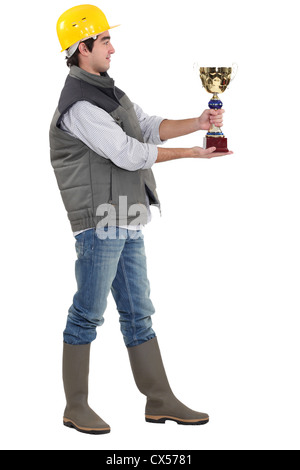 Builder holding trophy Stock Photo - Alamy