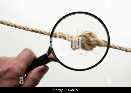 selective focus of man holding magnifying glass near coins on plaid ...