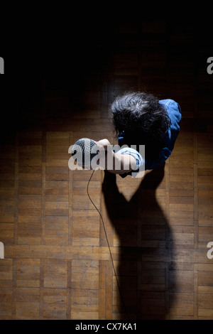Male singer holding microphone standing and performing on stage Stock ...