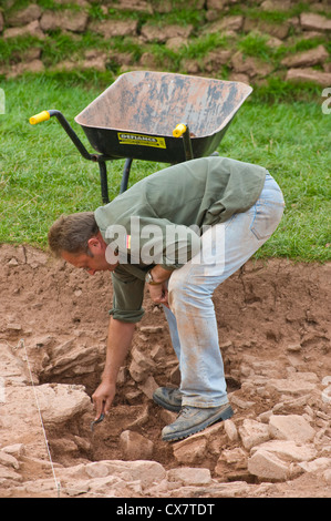 Archaeologist digging with trowel at a prehistoric neolithic site on ...