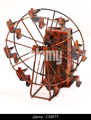 A well-used vintage Ferris wheel toy made of metal against a white ...