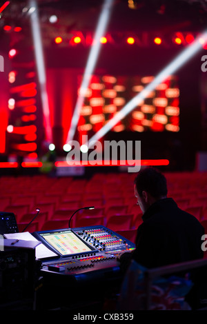 a man operating a digital lighting desk board in a theatre, designing ...