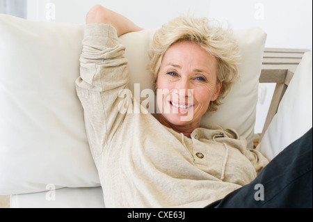 Portrait of mature woman reclining on white luxury sofa Stock Photo - Alamy