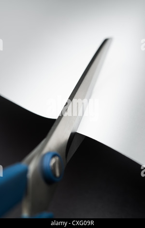 A pair of scissors cutting snipping a piece of paper Stock Photo - Alamy