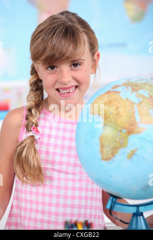 Schoolgirl girl studies globe at school on geography Stock Photo - Alamy