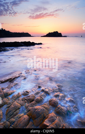 A breathtaking coastal landscape at sunset with rocky cliff jutting out ...