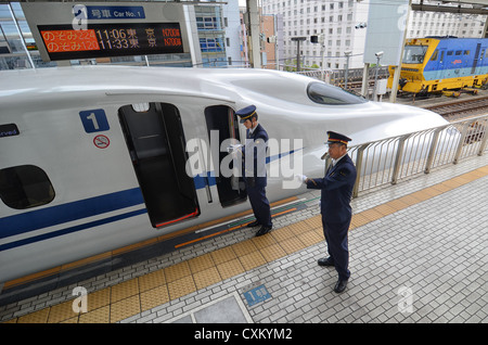 A station guard watches a JR 700 series (Japan railways) shinkansen ...