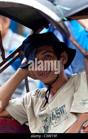 Close up portrait of rickshaw driver wearing khaki uniform blows smoke ...