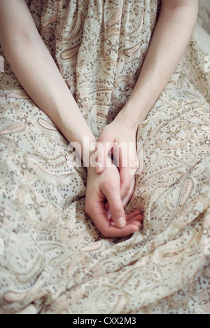Folded hands in lap of person sitting wearing a skirt with masculine ...