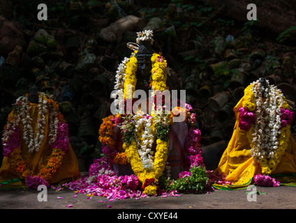 Altar with statues of deities adorned with flowers and offerings in a ...