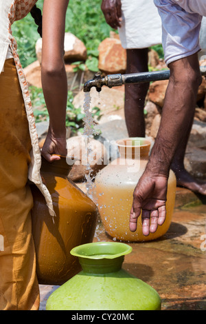 Rural Indian village man collecting water from a communal water tank ...