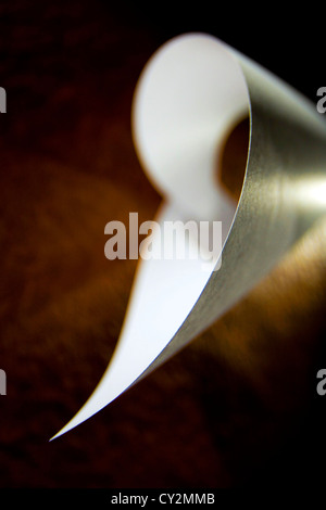 A white sheet of paper with a curved edge in A4 size on a orange ...
